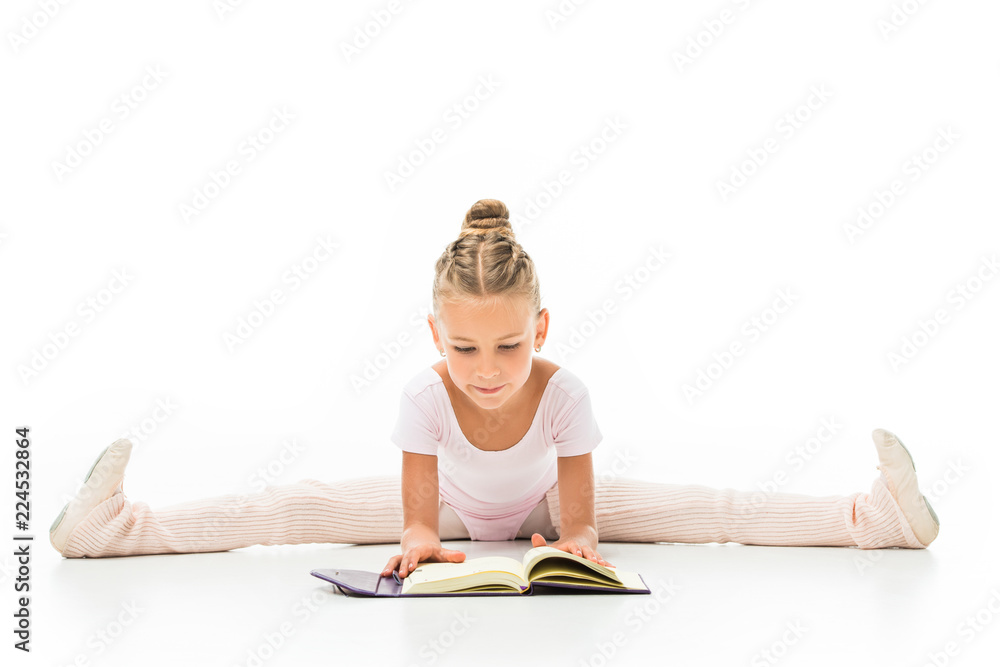 concentrated little ballerina reading book and doing twine isolated on ...