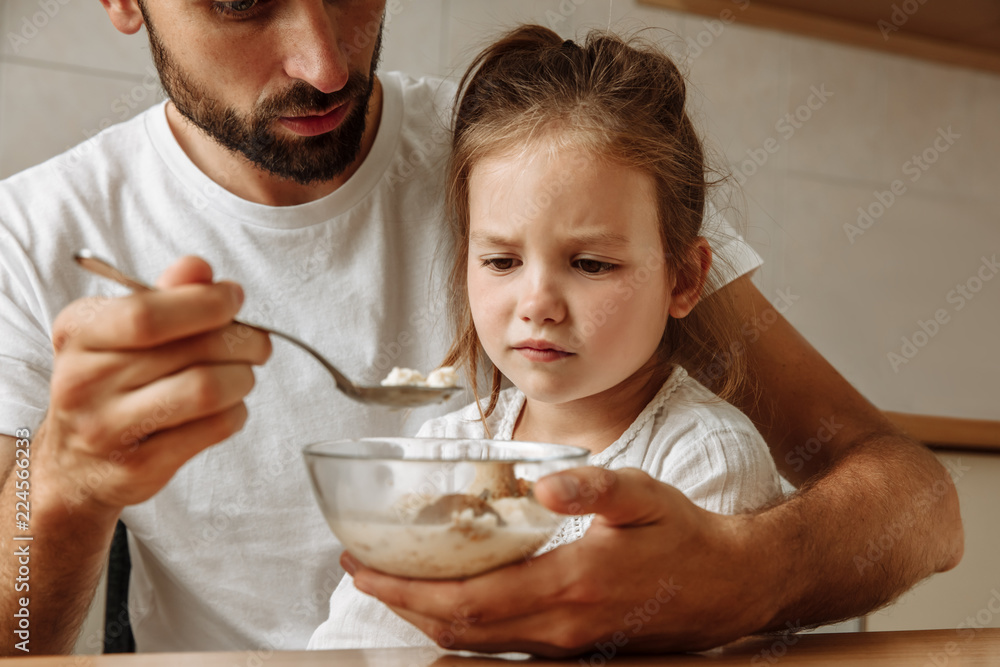 Family. Food. Parenthood. Dad is feeding his little daughter who is ...