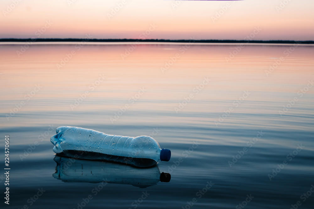 Concept of pollution, creative background. A plastic bottle floating in ...