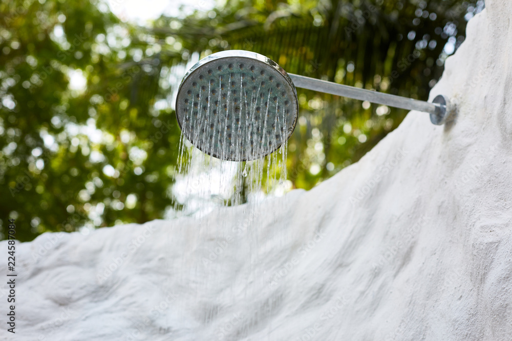 Outdoor rain shower head under palm trees and sunny beautiful blue sky ...