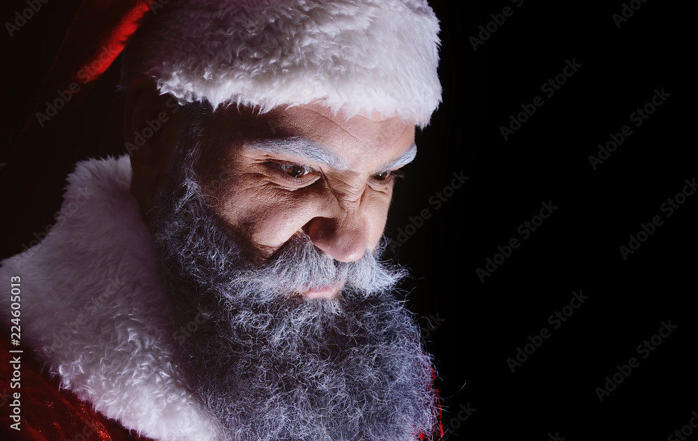 evil Santa Claus grimaces and scares a terrible face on a dark ...