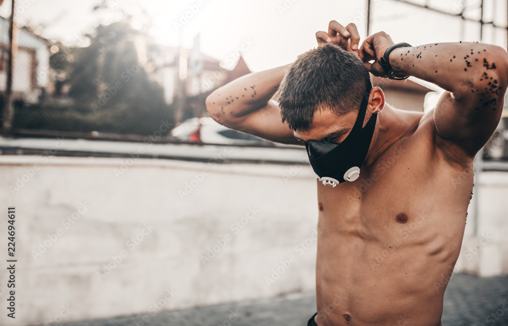 Caucasian muscular male wearing black training mask to increase load on ...