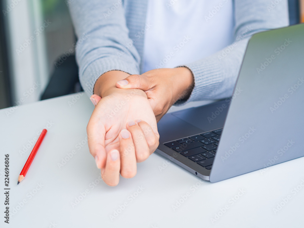 Closeup woman holding her wrist pain from using computer long time ...