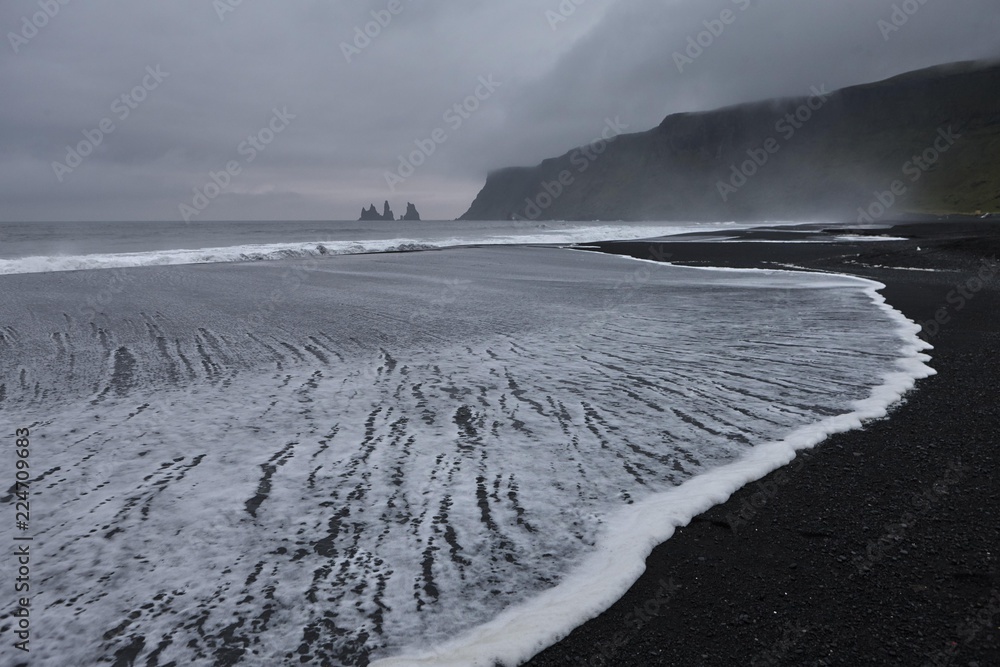 Expiring surf on the black beach near Vik i Myrdal, behind the ...