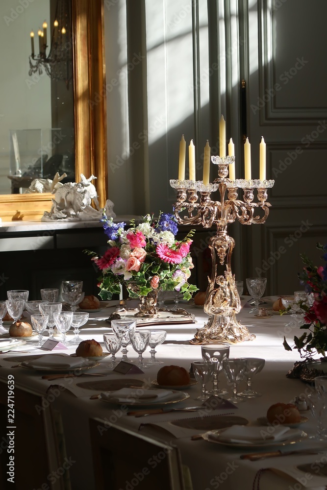 Chandelier et bouquet de fleurs sur une table dressée pour un repas de ...