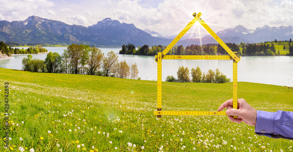 Makler hält Meterstab in Form von einem Haus als Symbol für Wohnen im ...