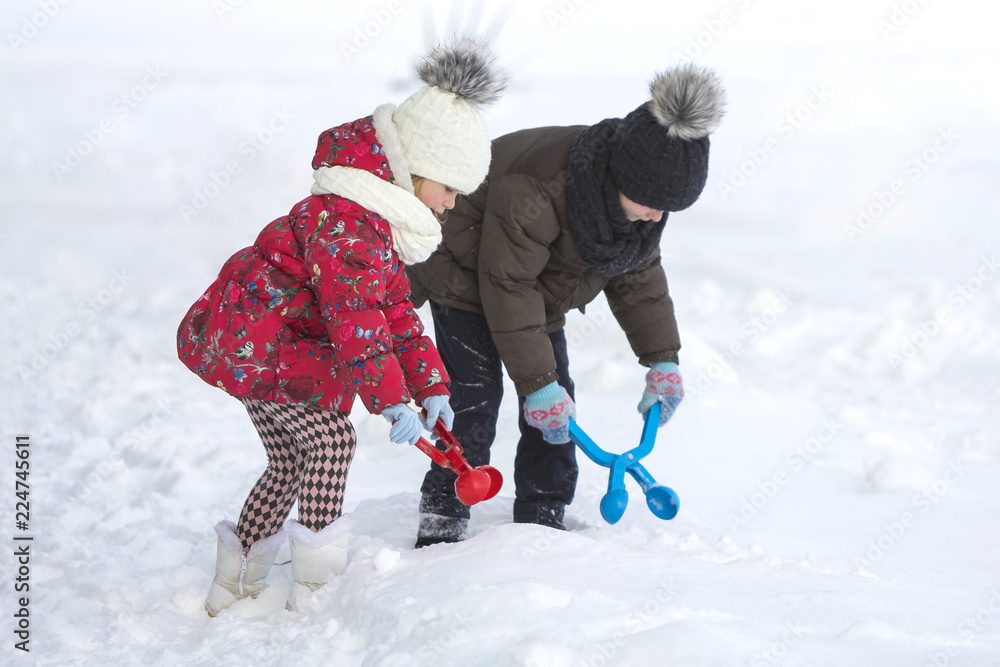 Two cute young children in warm clothing with bright snow clips playing ...