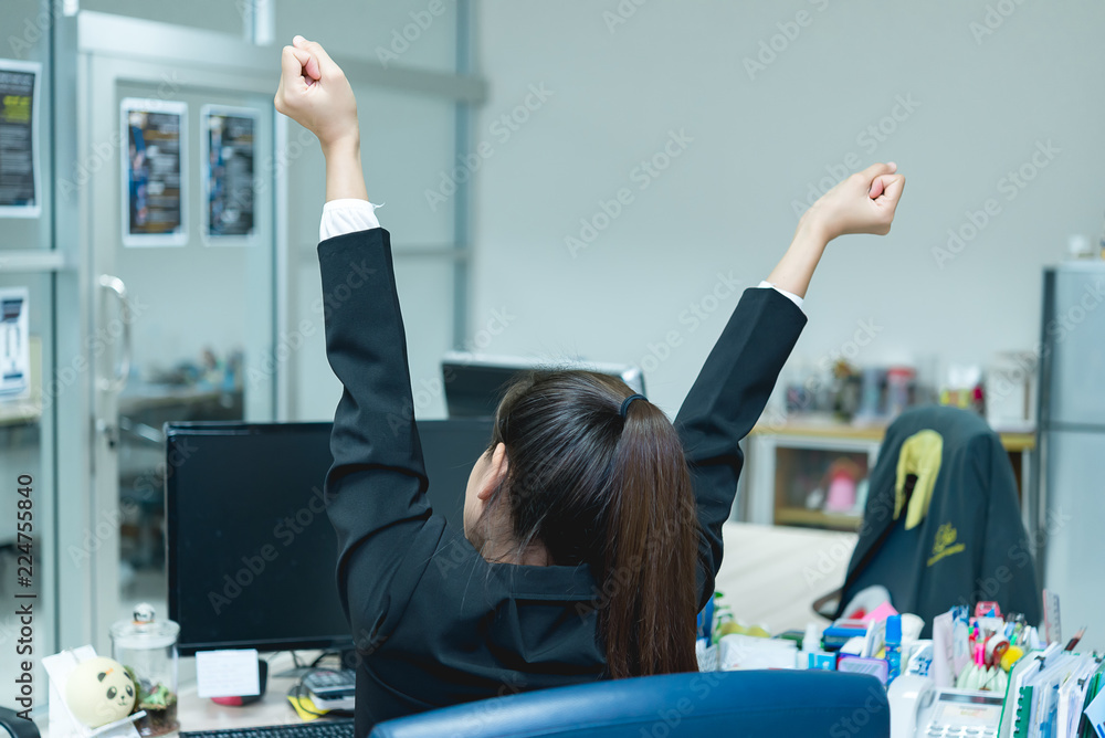 Asian officer woman stretching body at the desk of office from back ...