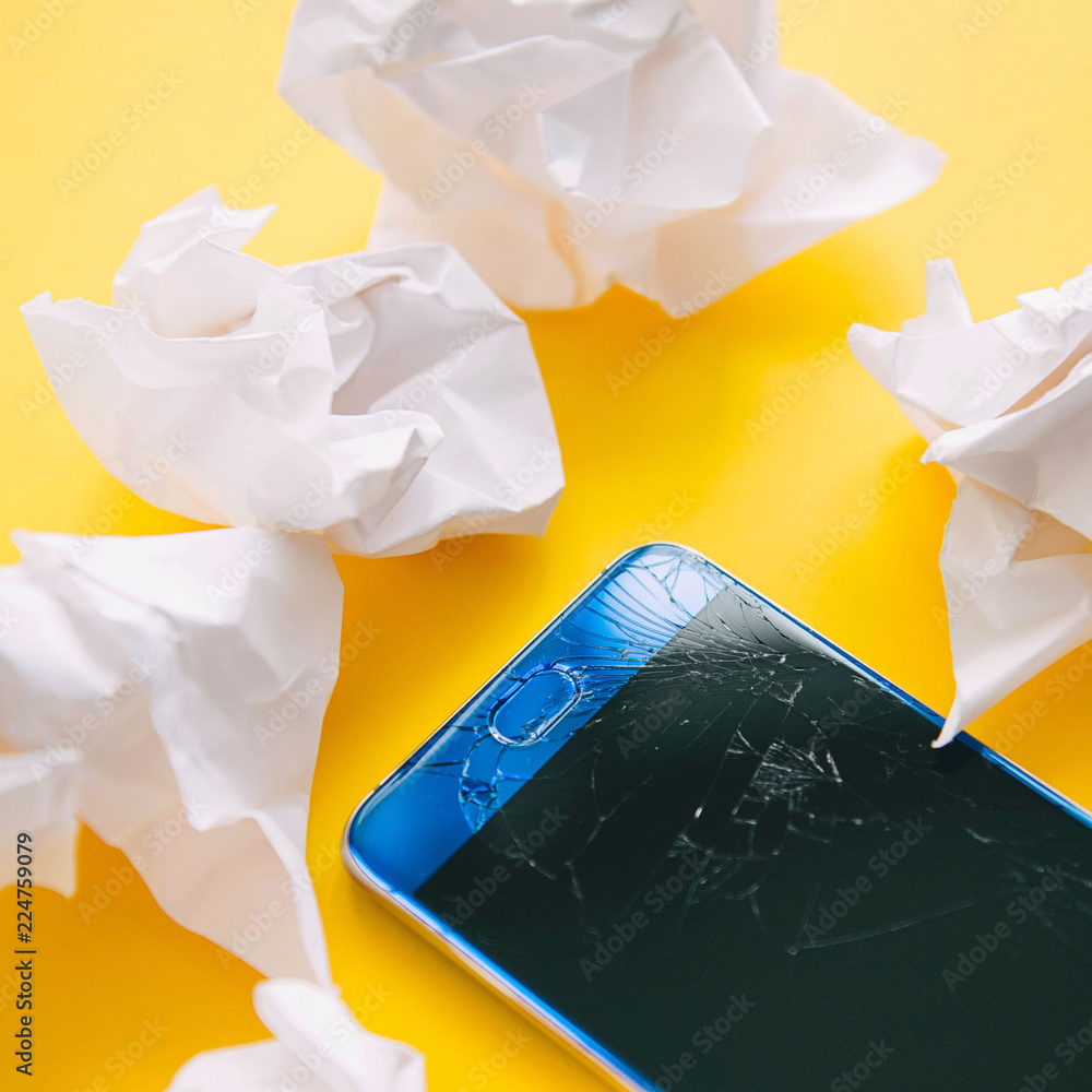 Smartphone with broken screen on yellow background with crumpled paper ...