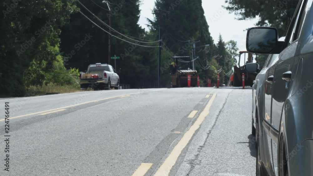 Cars stopped, waiting to be let past the road construction ahead as a ...