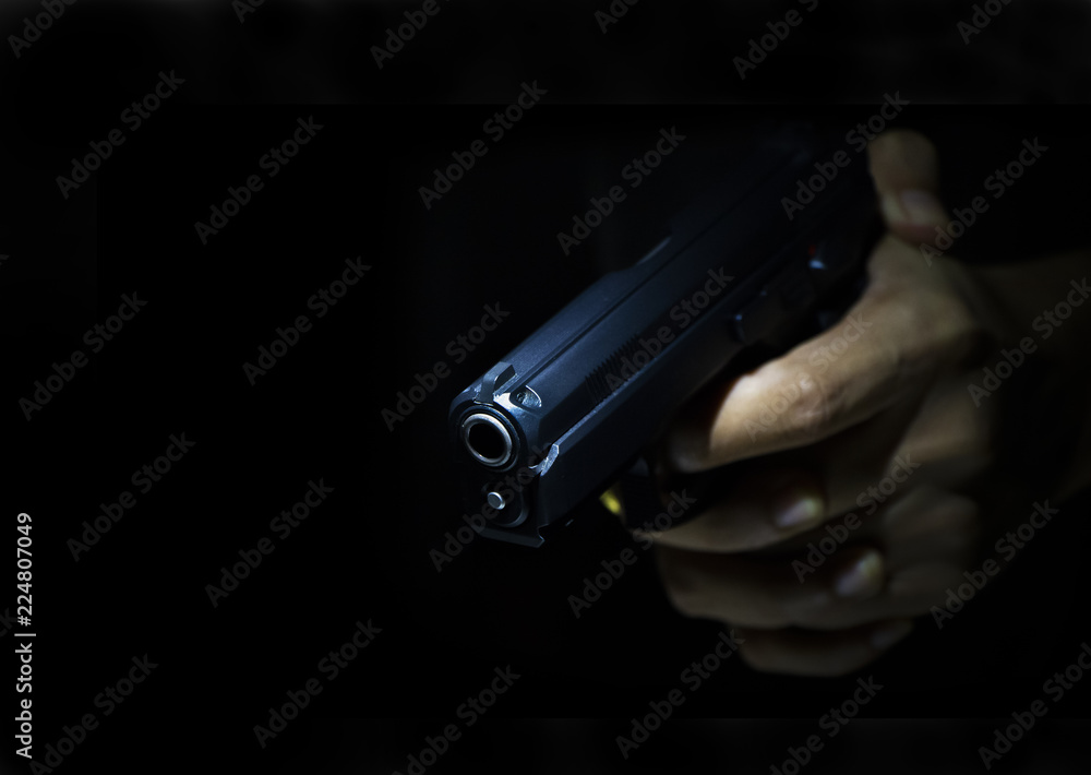 Gunman holding gun with dark background Stock Photo | Adobe Stock