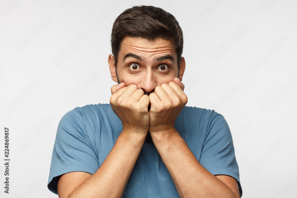 Astonished young male covering his mouth with both hands, looking ...