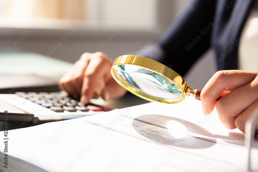 Businesswoman Examining Invoice Through Magnifying Glass Stock Photo ...