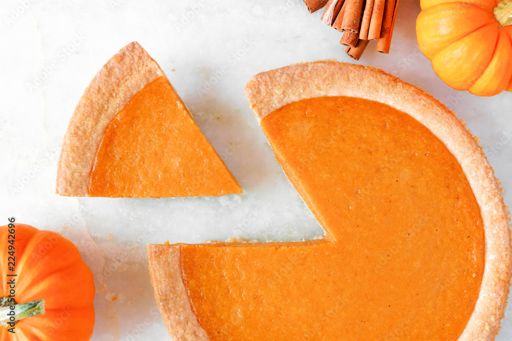 Pumpkin pie with slice removed. Top view, close up on a white marble ...