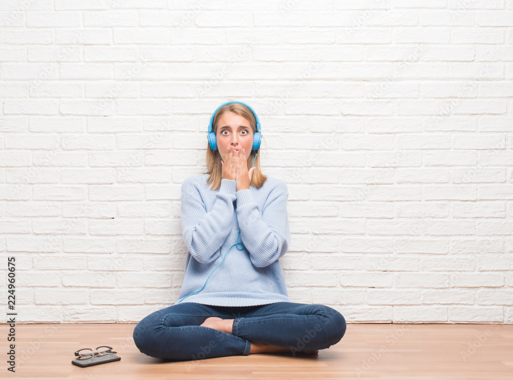 Beautiful young woman sitting on the floor listening music wearing ...