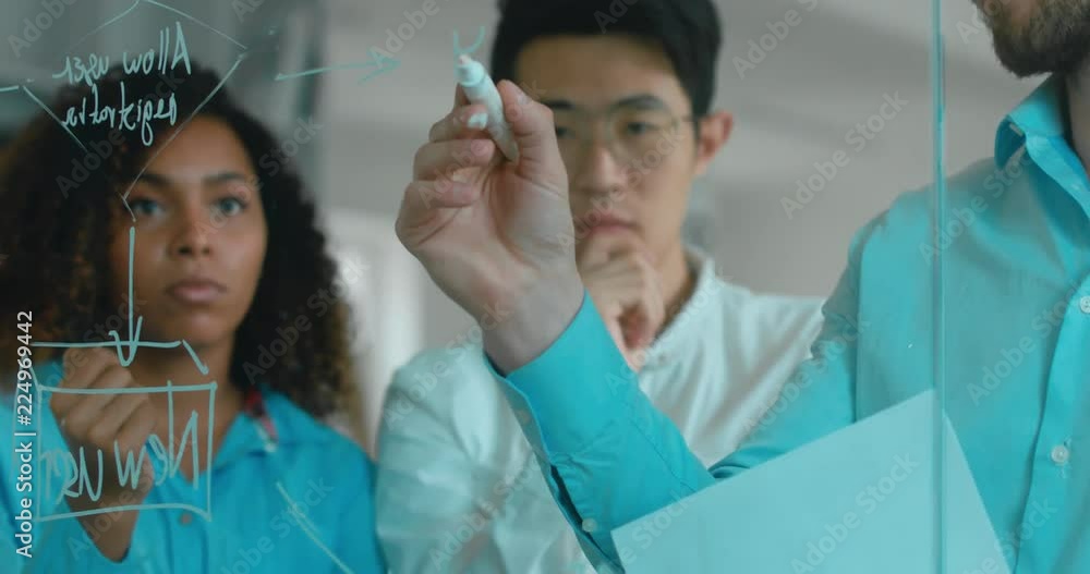 Multi racial team of employees drawing and discussing flowchart diagram ...