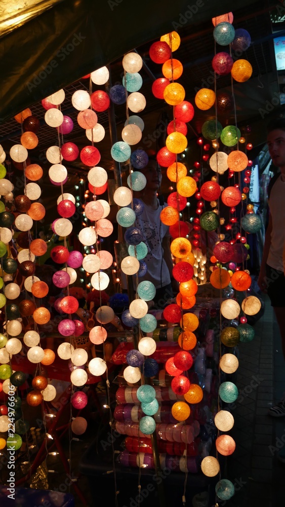 Multi-colored balls of lights hanging from a streetside stall attracts ...