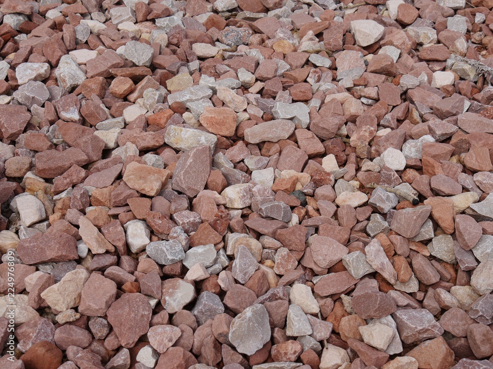 Small red and white rocks of different shapes and sizes in a garden ...