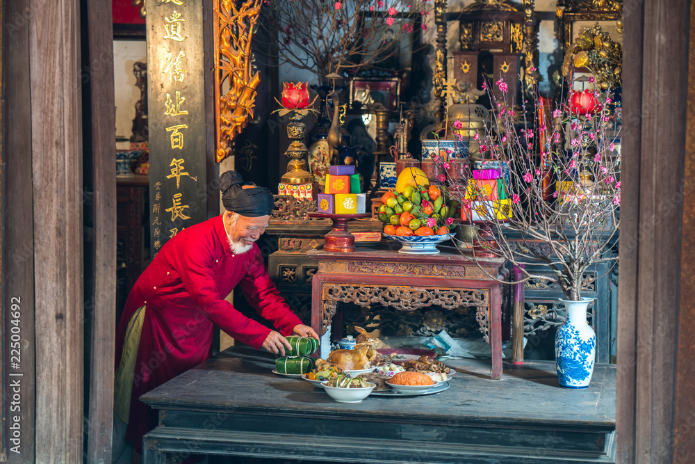 Old Vietnamese man preparing altar with foods for the last meal of year ...
