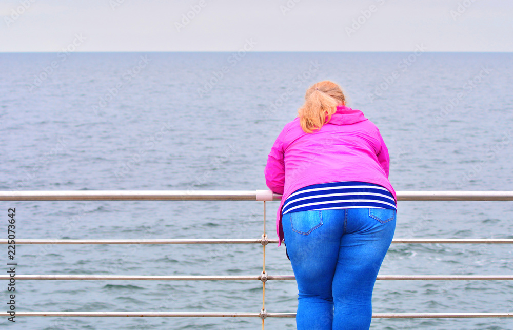 Lonely fat girl looks into the horizon of the sea. A problem with ...