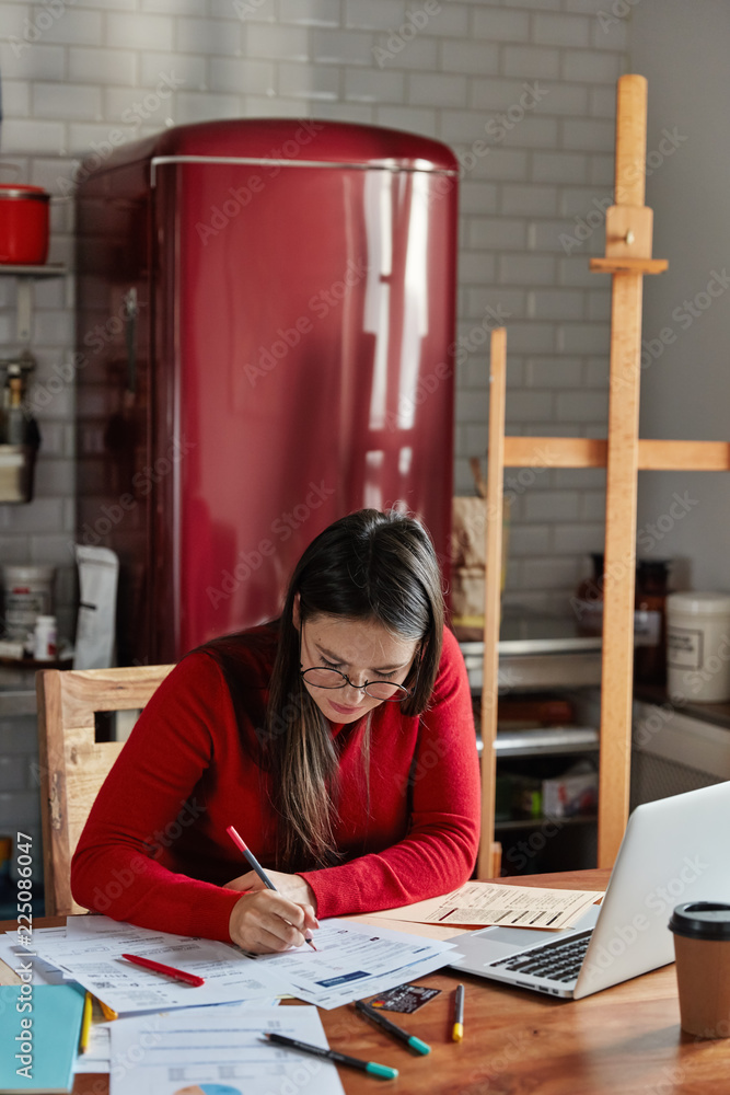 Vertical indoor shot of female banker makes financial report, poses at ...