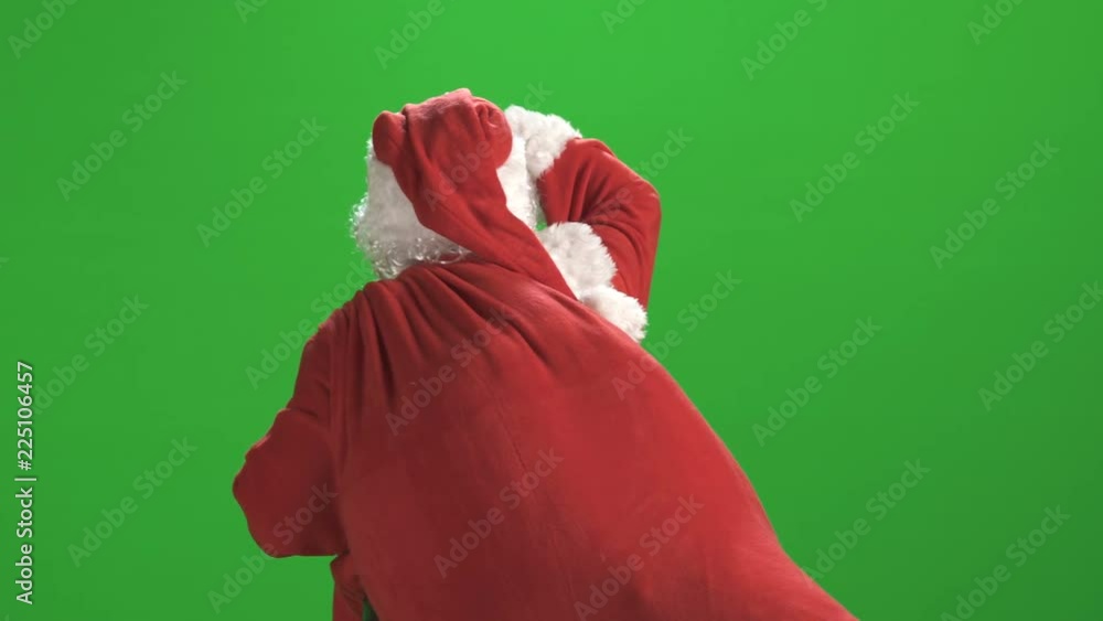 Merry Christmas. Santa Claus in a red suit is standing with his back ...
