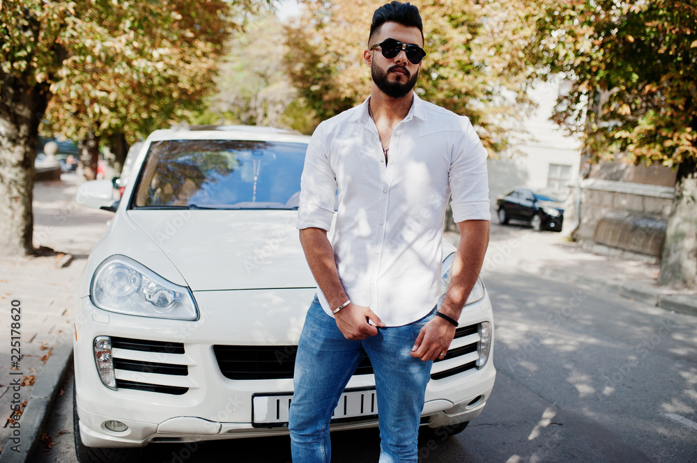 Stylish tall arabian man model in white shirt, jeans and sunglasses ...