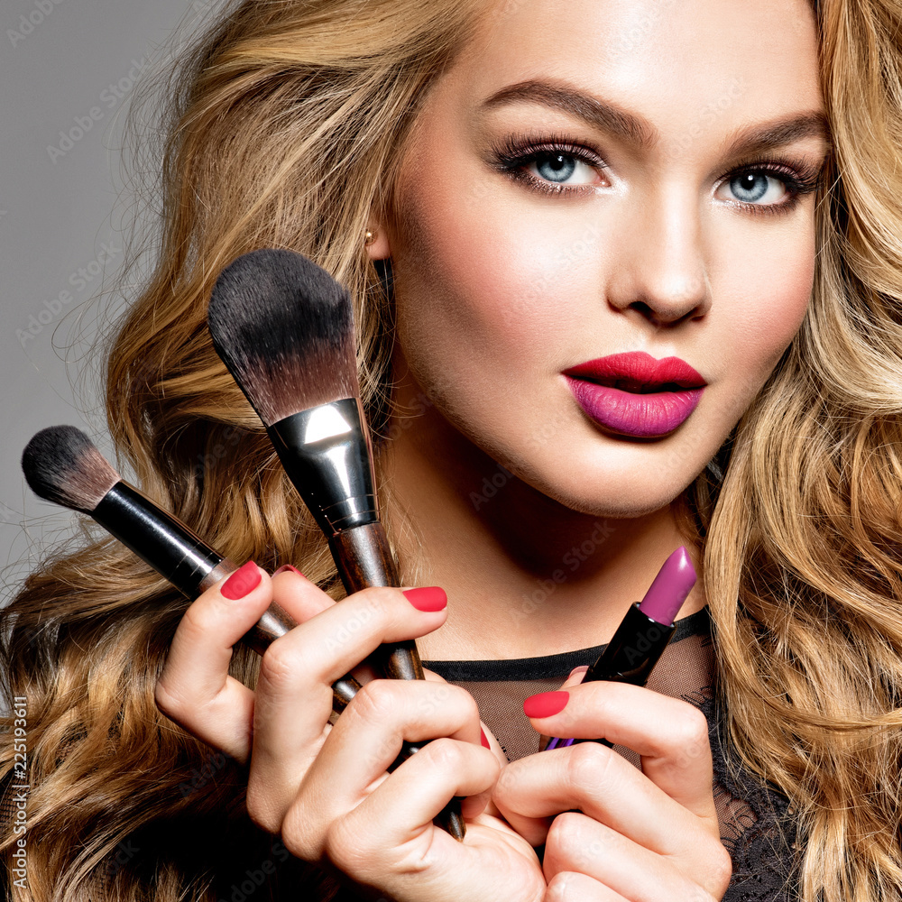 Beautiful woman holds cosmetic tools. Makeup. Stock Photo | Adobe Stock