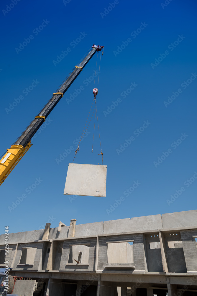 Construction site crane is lifting a precast concrete wall panel. Stock ...
