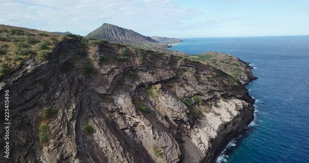 A drone shot above a cliffside beach rising and revealing another ...
