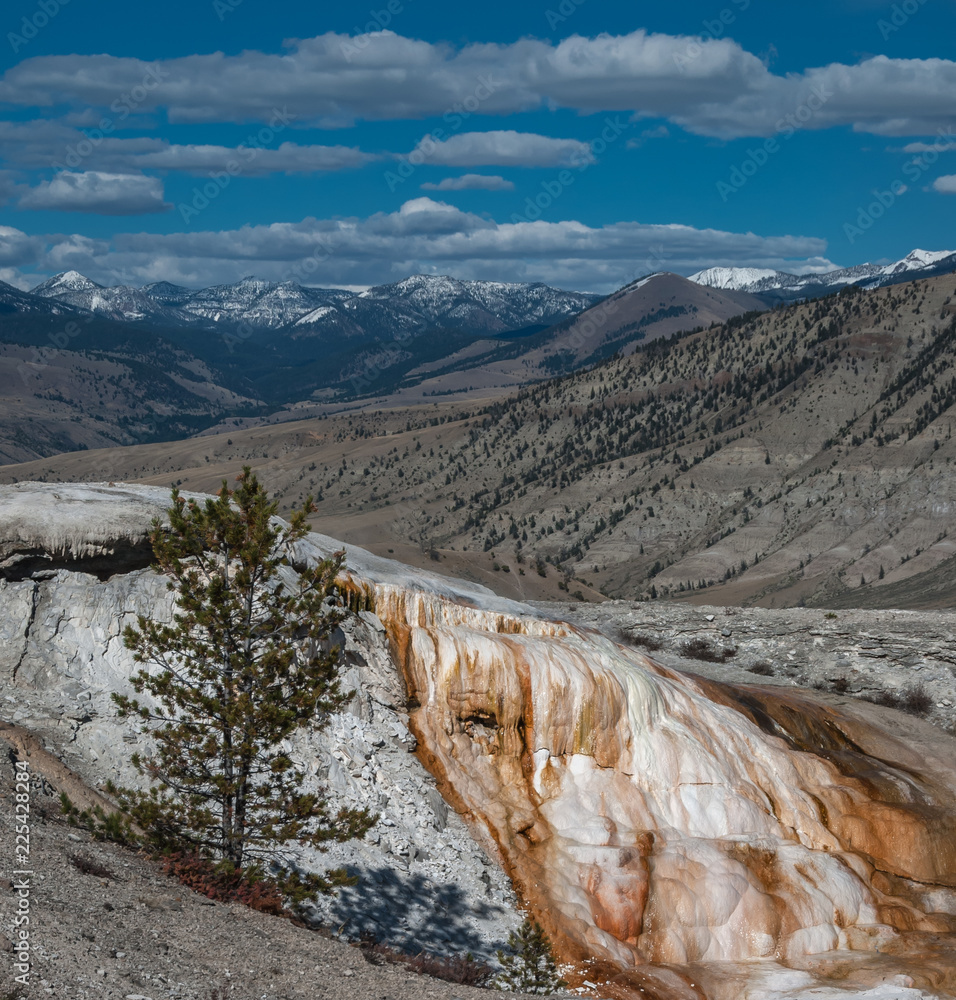 Snow-capped mountains rise in the distance behind a white and rust ...