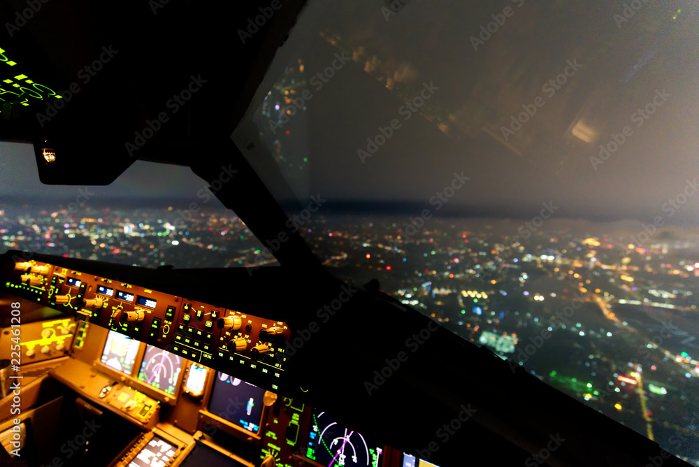 Inside cockpit of commercial airplane while flying over city in night ...