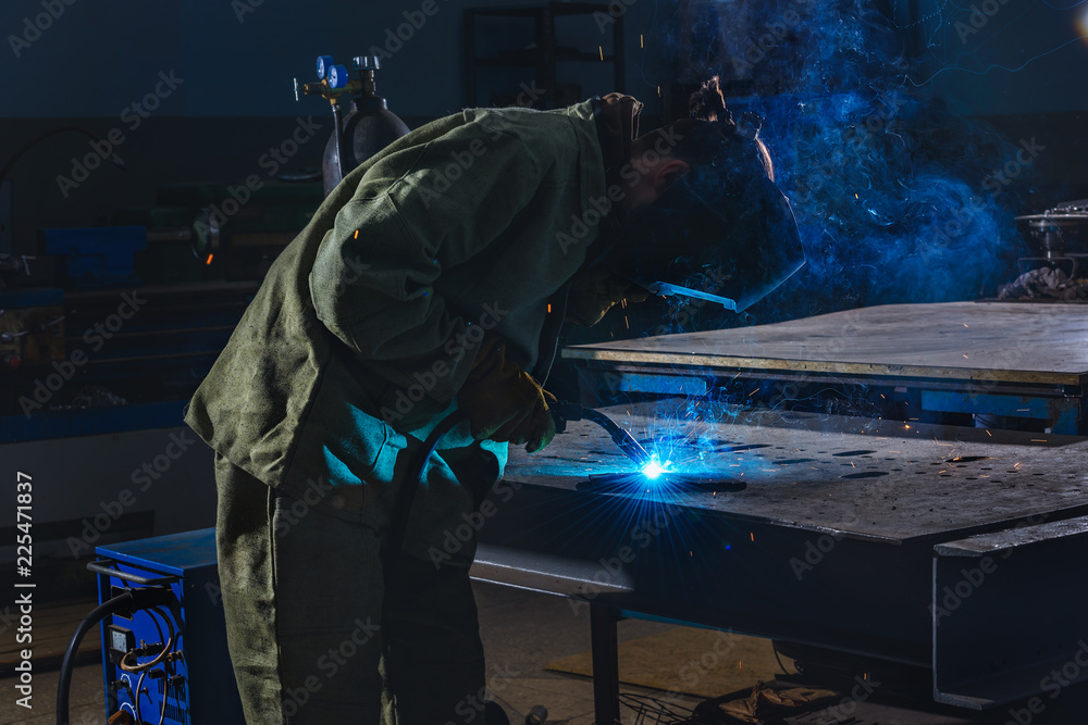 side view of welder in protection mask brazing metal at factory Stock ...