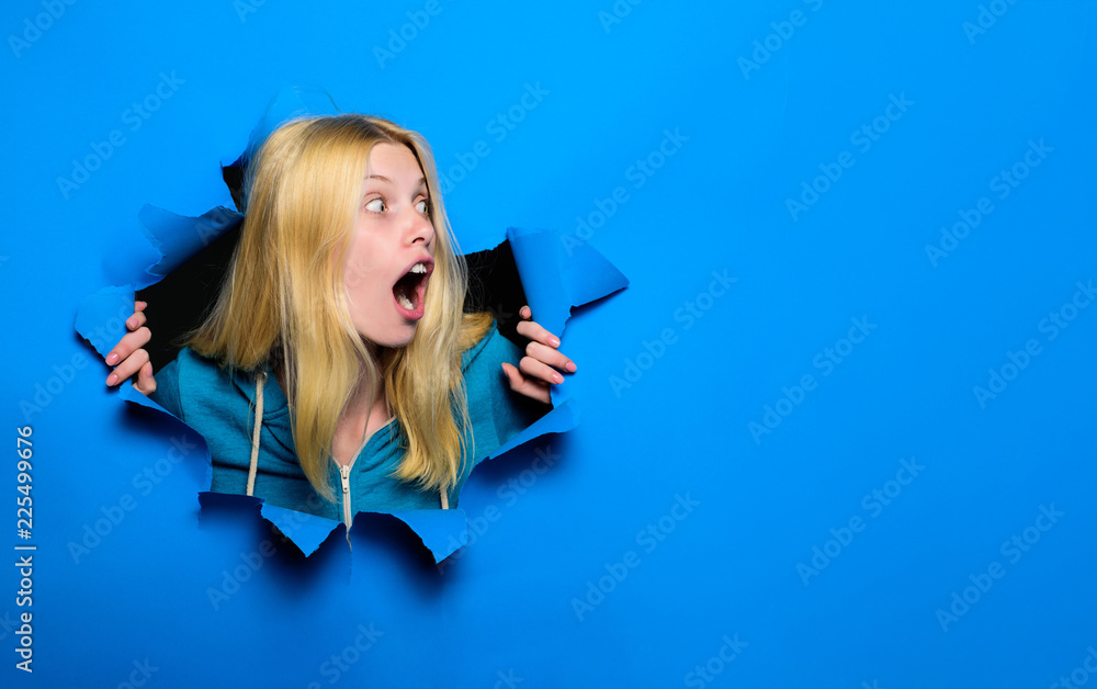 Surprised woman looking through hole in paper wall. Shocked girl making ...