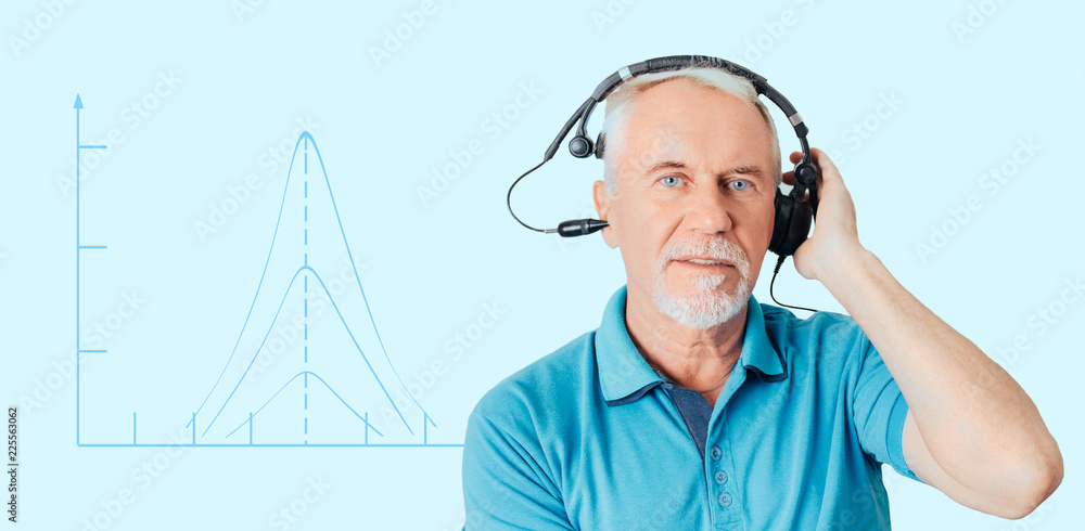 Senior man getting a hearing test , tympanogram on the background ...