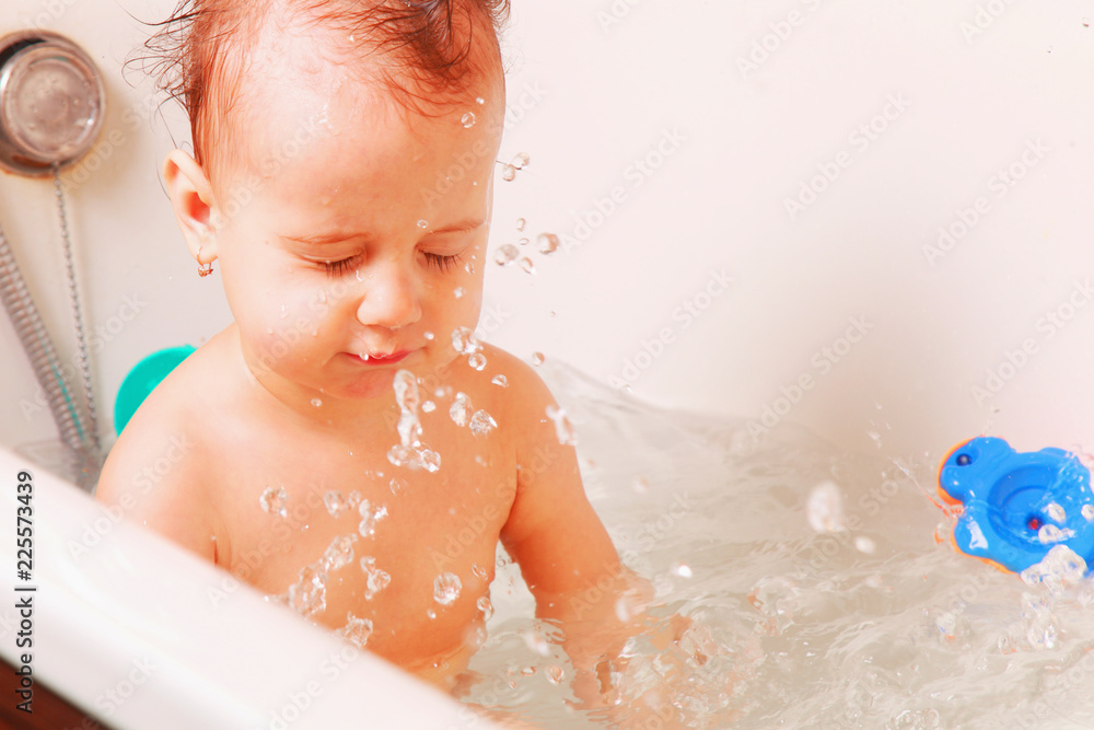 Beautiful little baby girl bathing in the water in the bath as symbol ...
