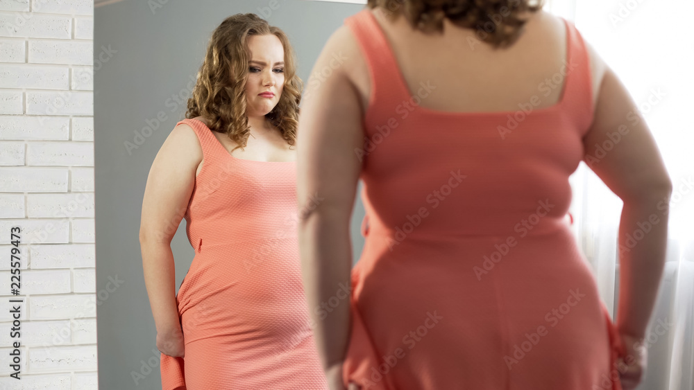 Plump female looking in mirror, upset about her belly, overweight ...