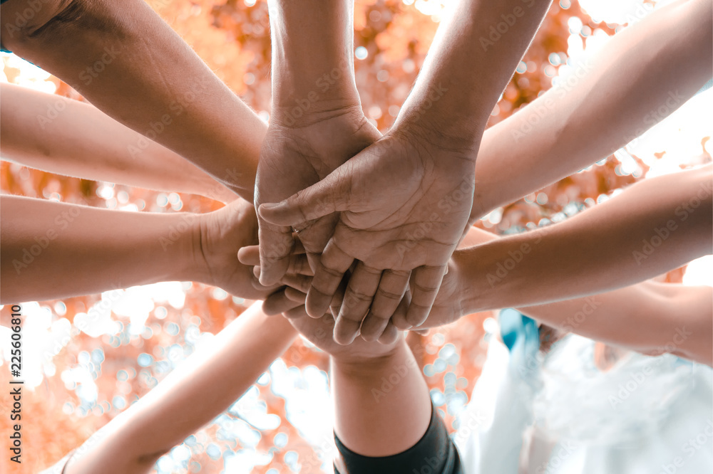 Teamwork concept; many people standing hands together in field before ...