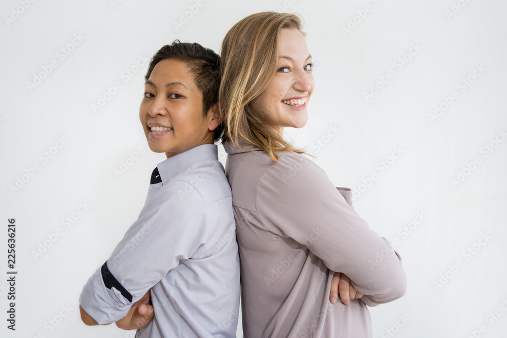 Smiling women standing back to back. Multiethnic ladies posing with ...