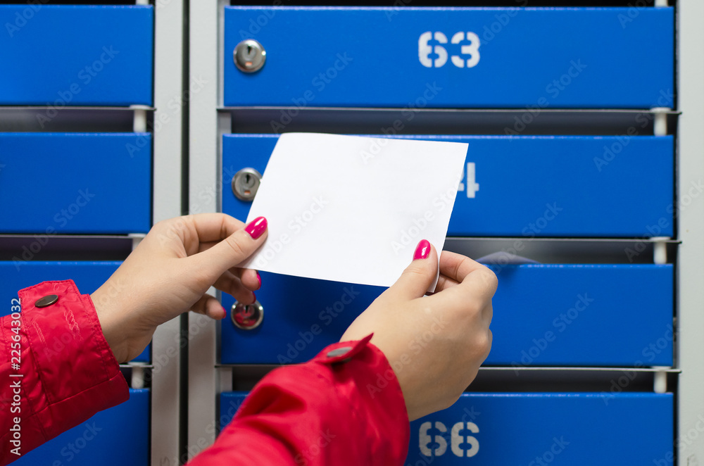 Blank letter paper page in female hand on a blue mailboxes background ...