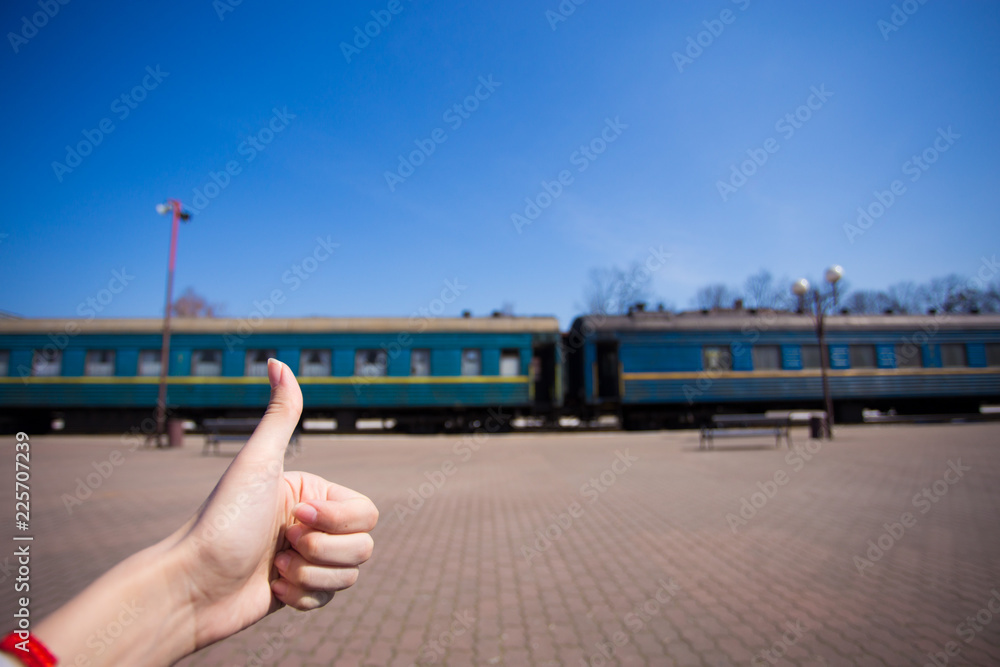 tourist showing thumb up with blurred train railway station on ...
