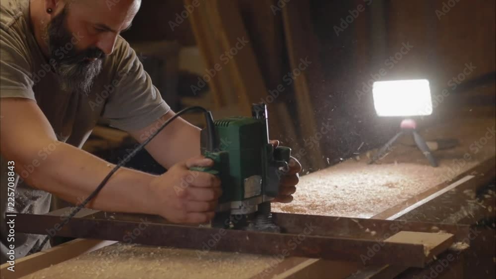 Slow motion view of a strong and masculine wood worker guiding a power ...