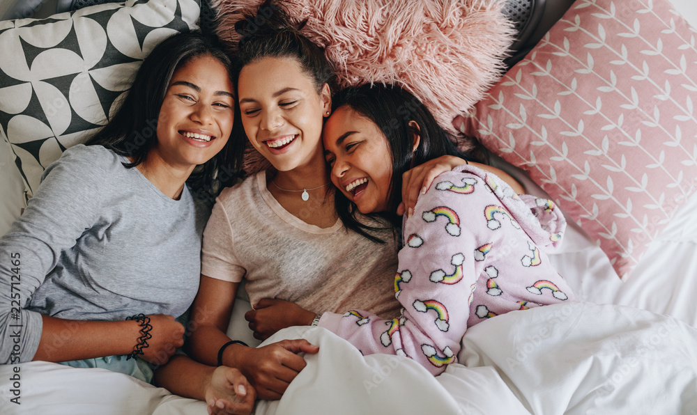 Girls lying on bed together having a sleepover Stock Photo | Adobe Stock
