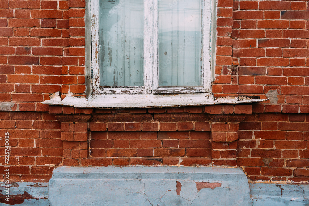 Old destroyed brick wall. White wooden window with iron window sill ...