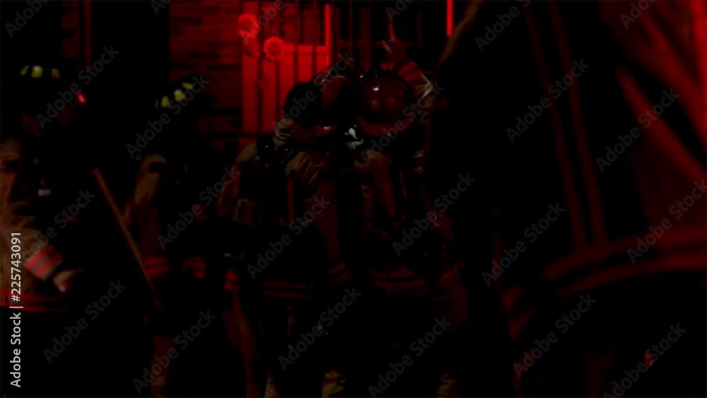 Firefighters pointing at a structure fire at night with flashing red ...