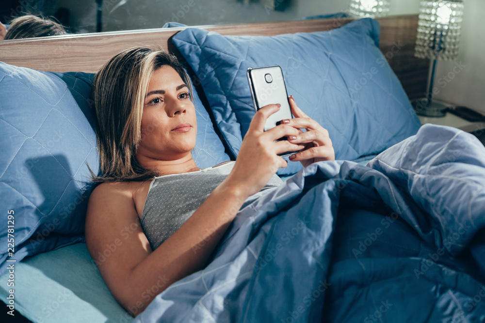 Women are using the smart phone on the bed before she sleeping at night ...