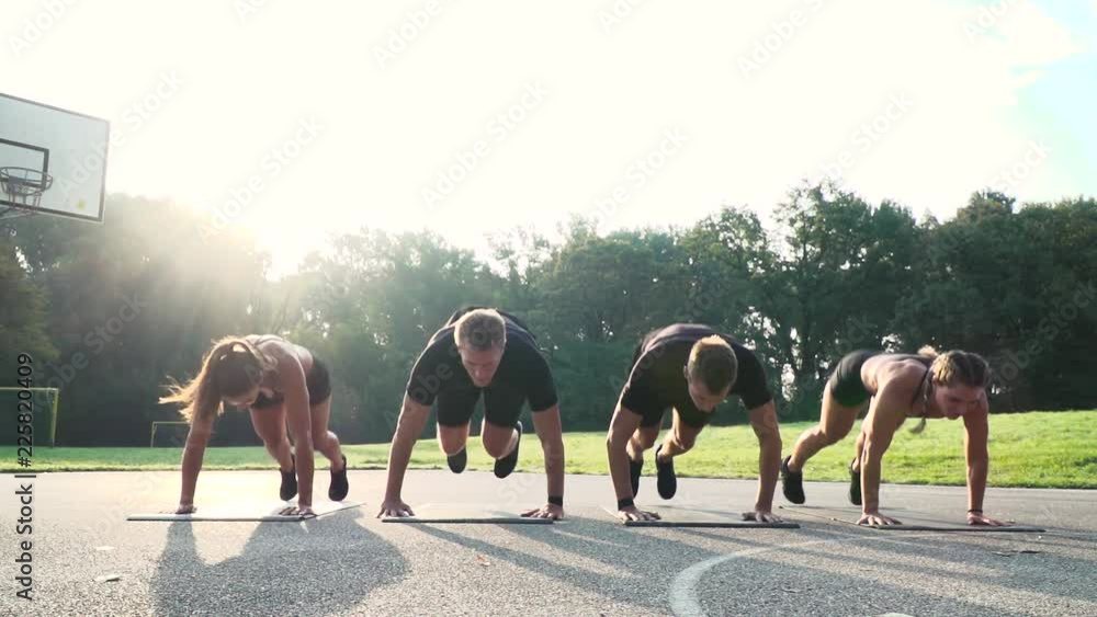 two girls and two boys doing 6 count burpees outdoor in the morning sun ...