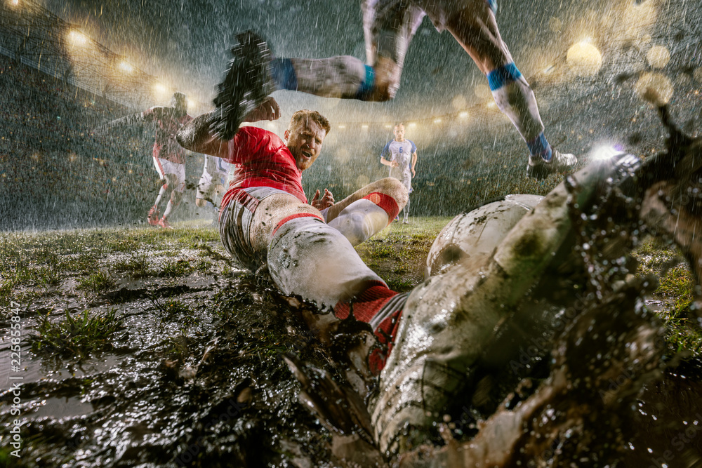 Soccer players performs an action play on a professional night rain ...