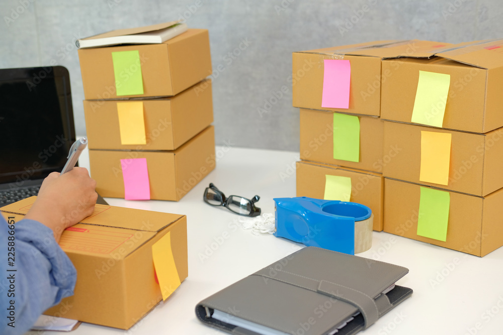 startup business owner writing address on cardboard box. woman seller ...