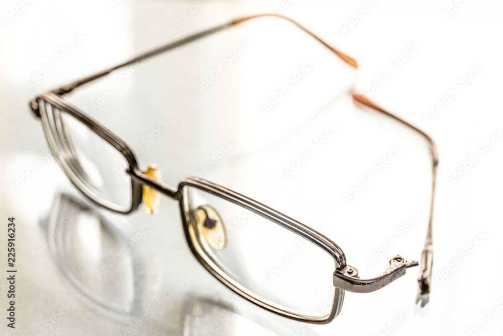 Eyeglasses with a broken handle on a bright background. Limited depth ...
